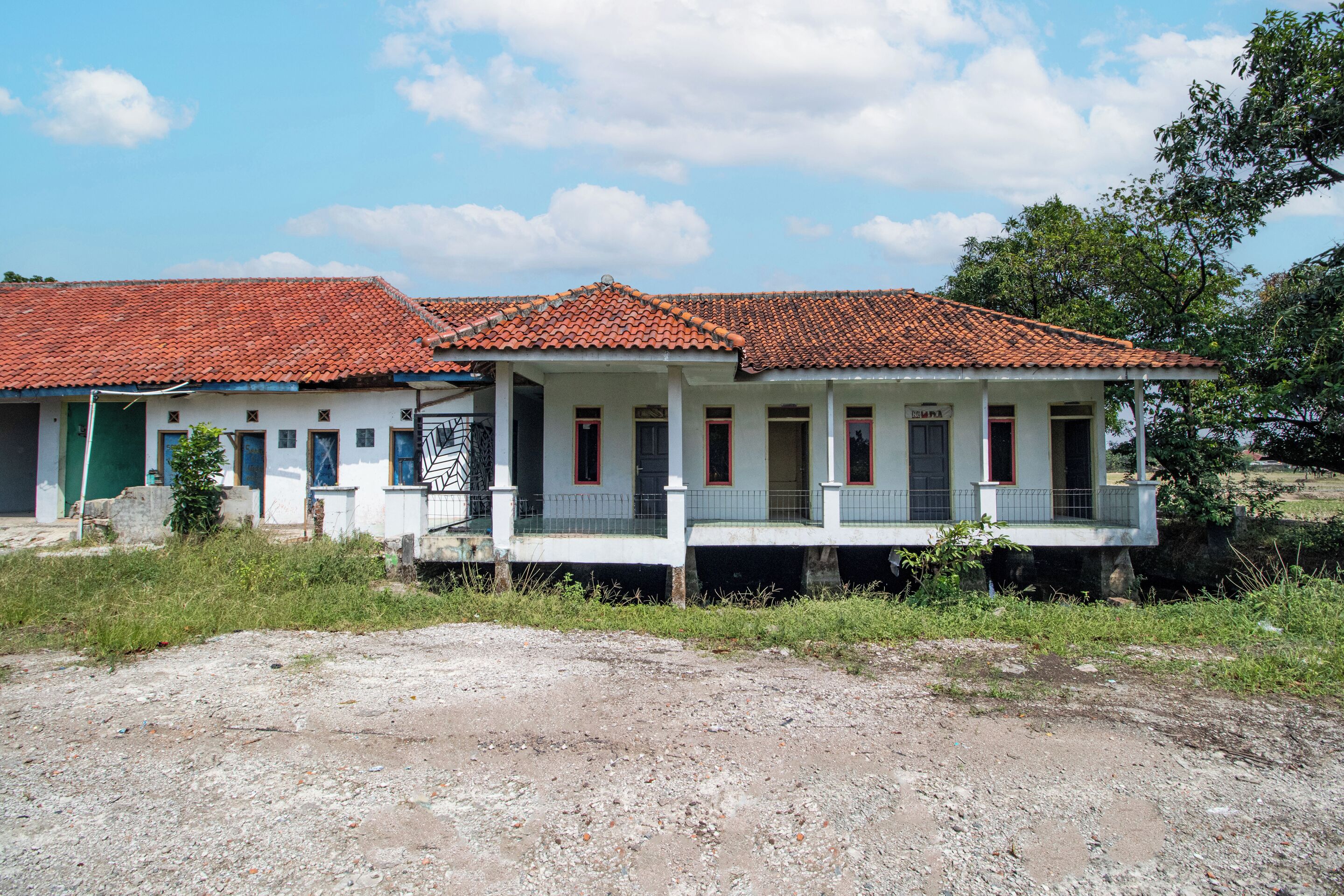Um edifício de dois andares com telhado de telhas vermelhas e uma varanda.