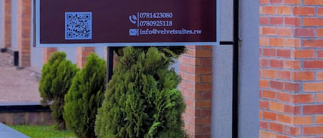 Placa para 'Velvet Suites' com informações de contato e um código QR.