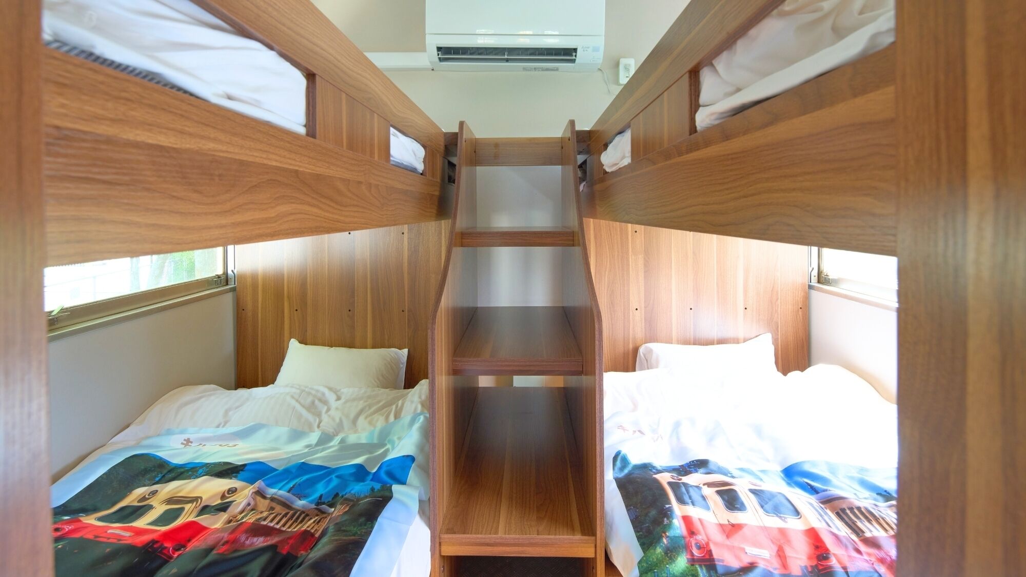 Quarto com beliche, escada de madeira, roupa de cama branca e uma janela.