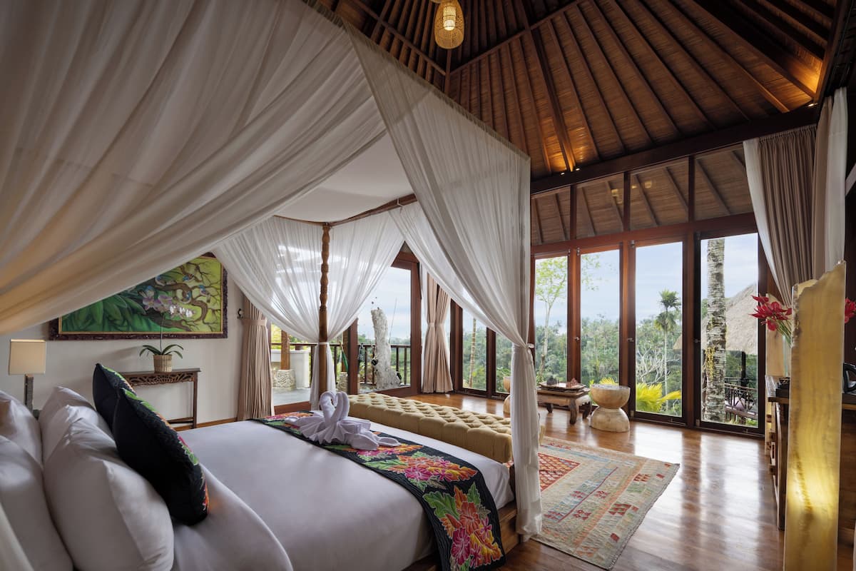 Um quarto espaçoso com uma cama grande, um dossel e vista para o exterior.
