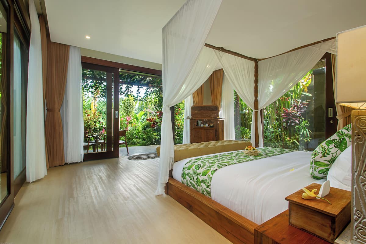 Um quarto espaçoso com uma cama grande, uma mesa de cabeceira de madeira e uma estrutura de dossel.