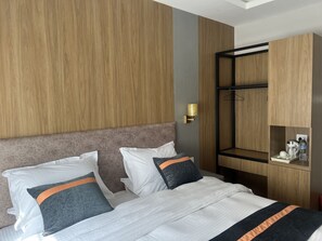 Quarto de hotel com cama, guarda-roupa e mesa de cabeceira com abajur.