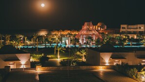 Resort com piscina, palmeiras e um edifício iluminado com cúpula.