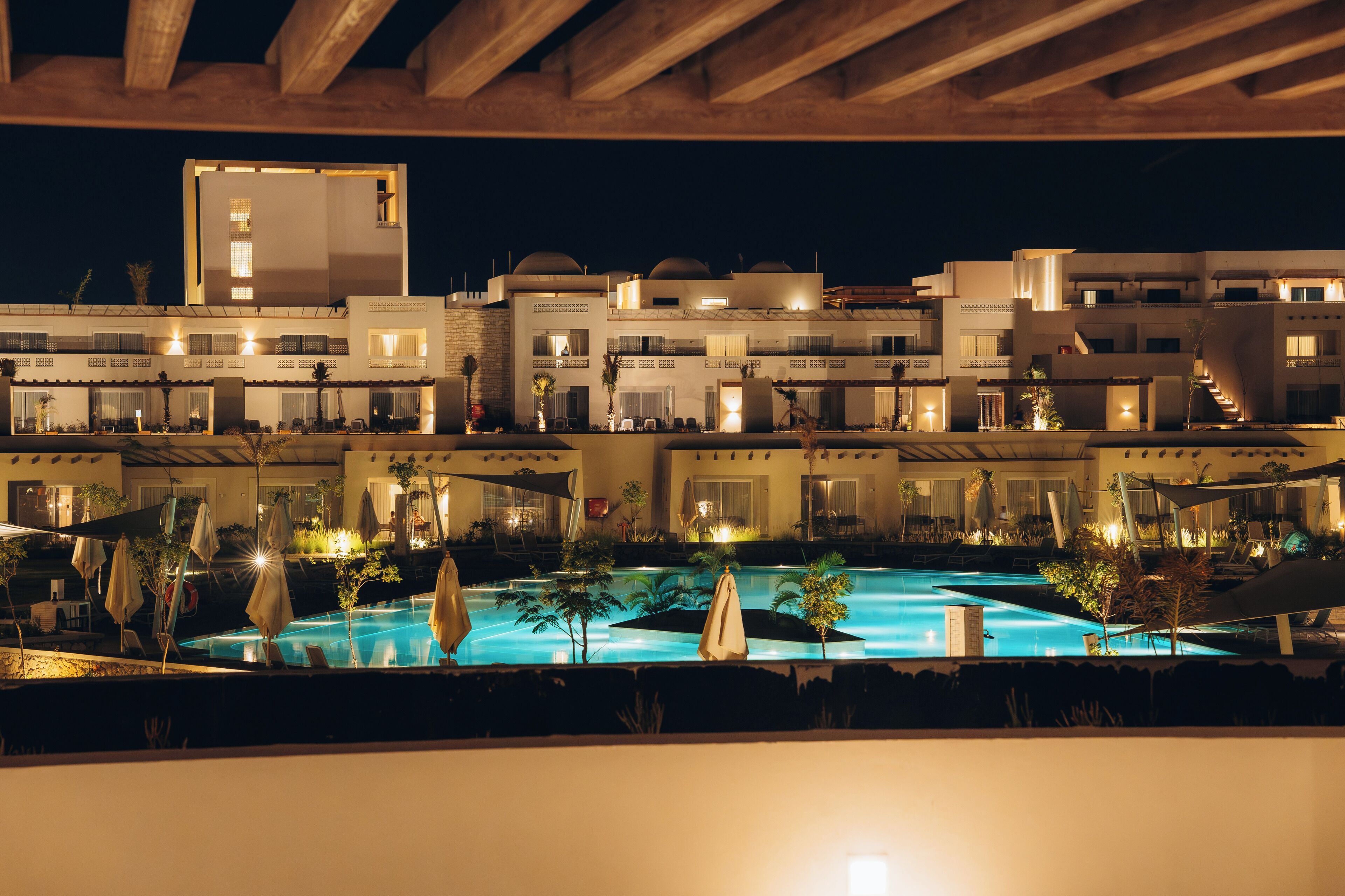 Um hotel com piscina, área de estar externa e espaço coberto.