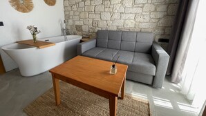 Um banheiro moderno com banheira, um sofá cinza e uma mesa de madeira.
