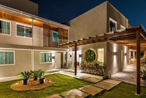 Uma casa moderna com alpendre coberto, gramado bem cuidado e um jardim circular.