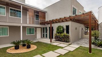 Uma casa moderna de dois andares com varanda coberta, um pequeno jardim e escadaria que dá acesso ao andar superior.