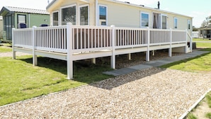 Uma casa móvel com um deck branco e varanda coberta.