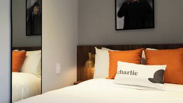 Quarto de hotel com cama bem arrumada, espelho na parede e quadro emoldurado sobre a cama.