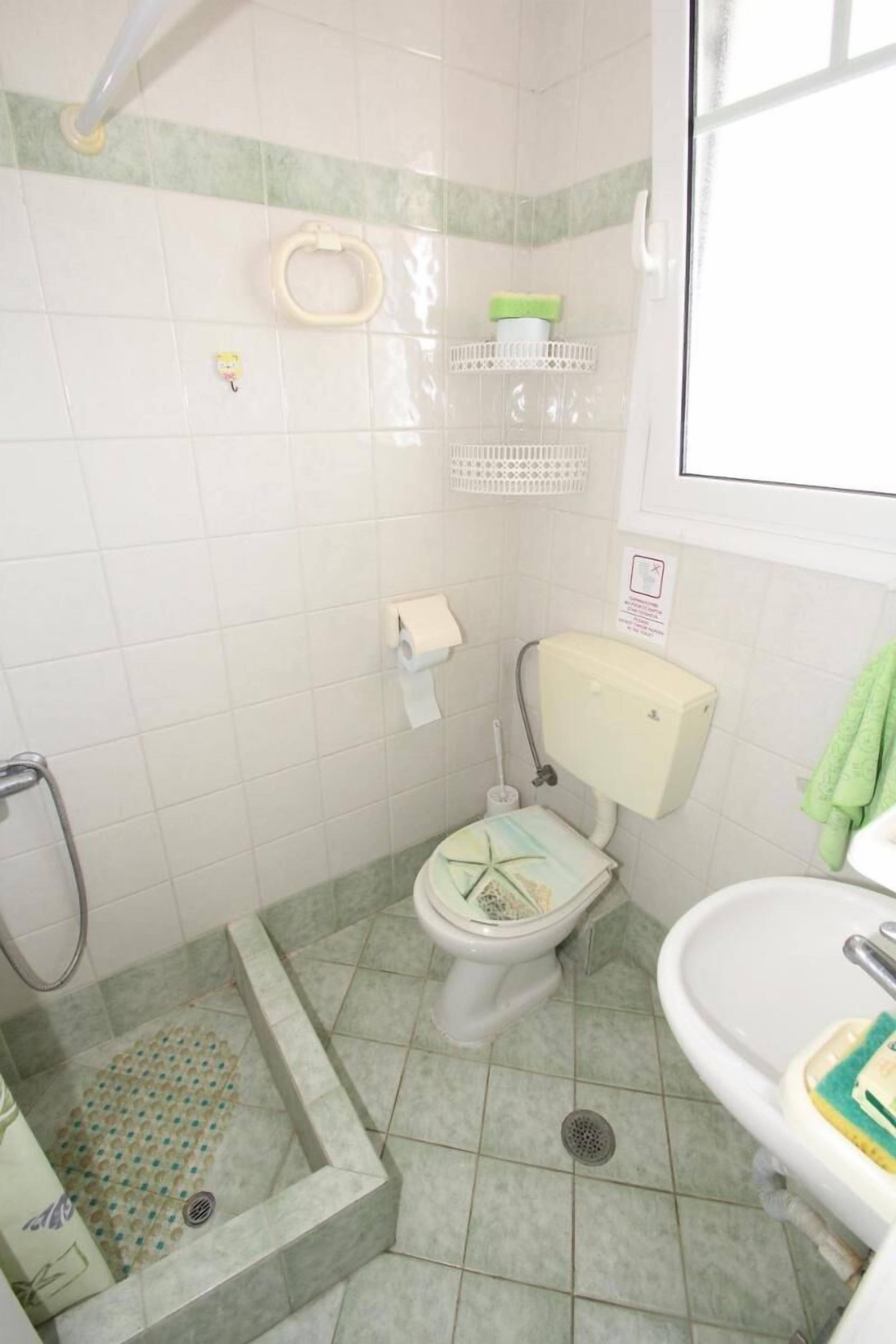 Casa de banho com sanita, zona de duche e lavatório.