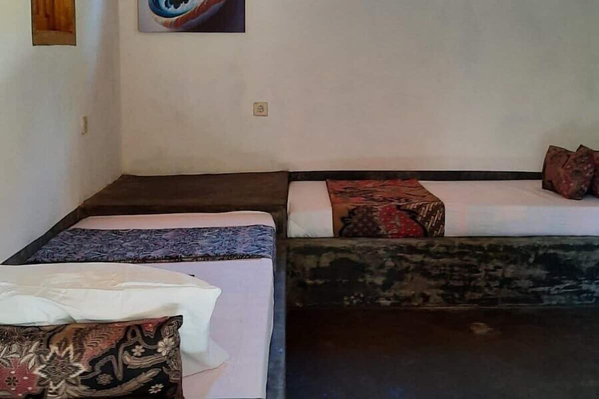 Quarto com duas camas, uma porta de madeira e duas pinturas na parede.