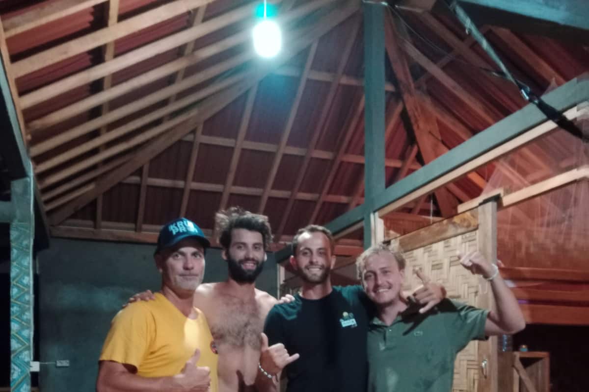 Um grupo de quatro pessoas em um espaço interno, com vigas de madeira no teto e uma parede verde.