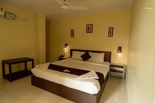 Quarto de hotel com uma cama grande, mesas de cabeceira, luminárias fixadas na parede e um ventilador de teto.