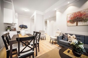 Uma sala de estar moderna com um sofá cinza, uma mesa de jantar com cadeiras e uma mesa de centro com um vaso.