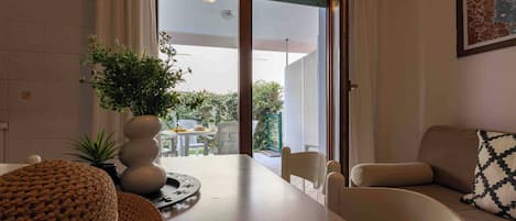 Uma sala de estar moderna com um sofá, uma mesa redonda de fibra natural e um vaso de planta.