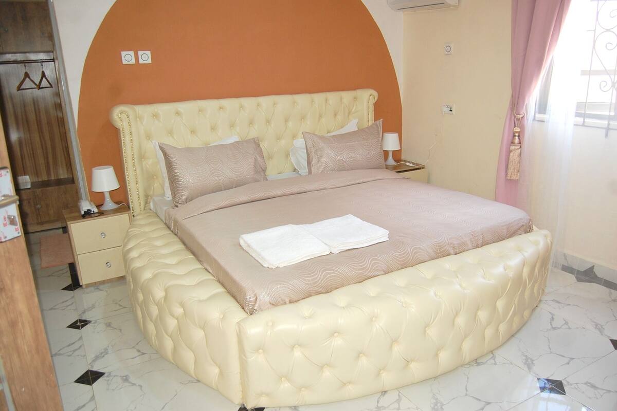 Quarto com uma cama grande, duas mesas de cabeceira, um guarda-roupa e porta de banheiro.