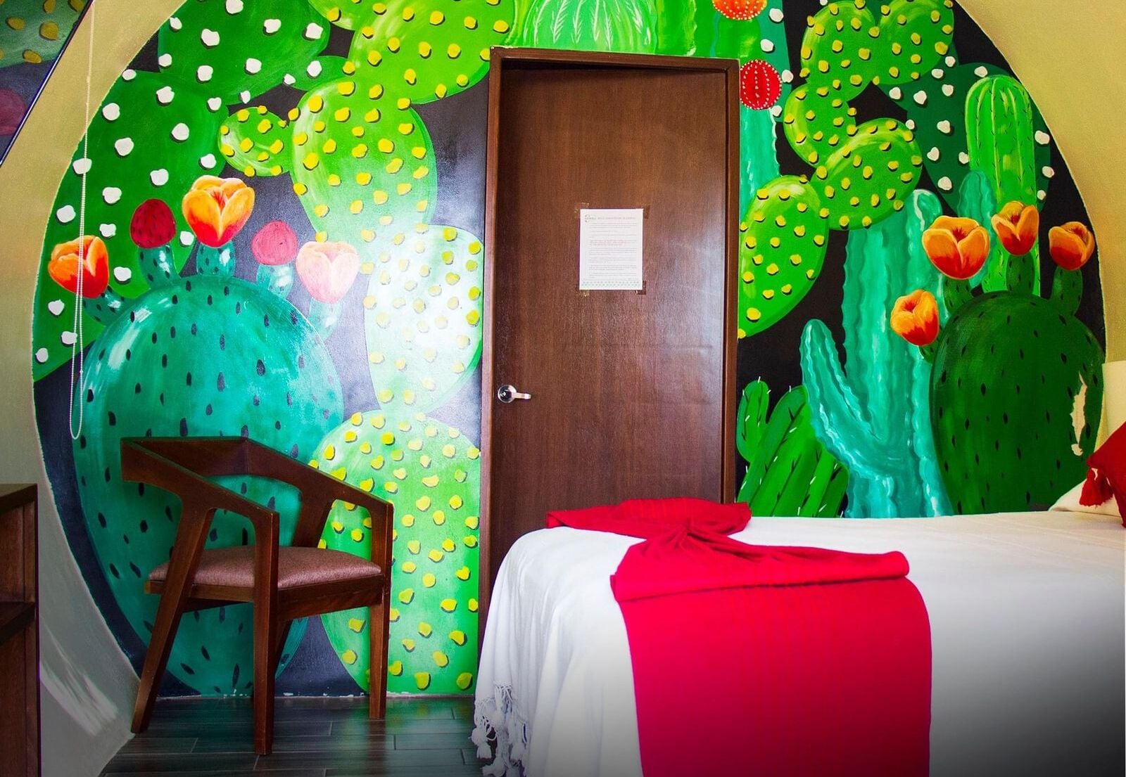 Um quarto com uma cama, uma cadeira de madeira e uma porta.