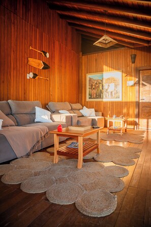 Um quarto acolhedor com paredes de madeira, um sofá, uma mesa e um quadro.