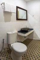 Casa de banho com sanita, lavatório de pedra, espelho e pavimento em mosaico.