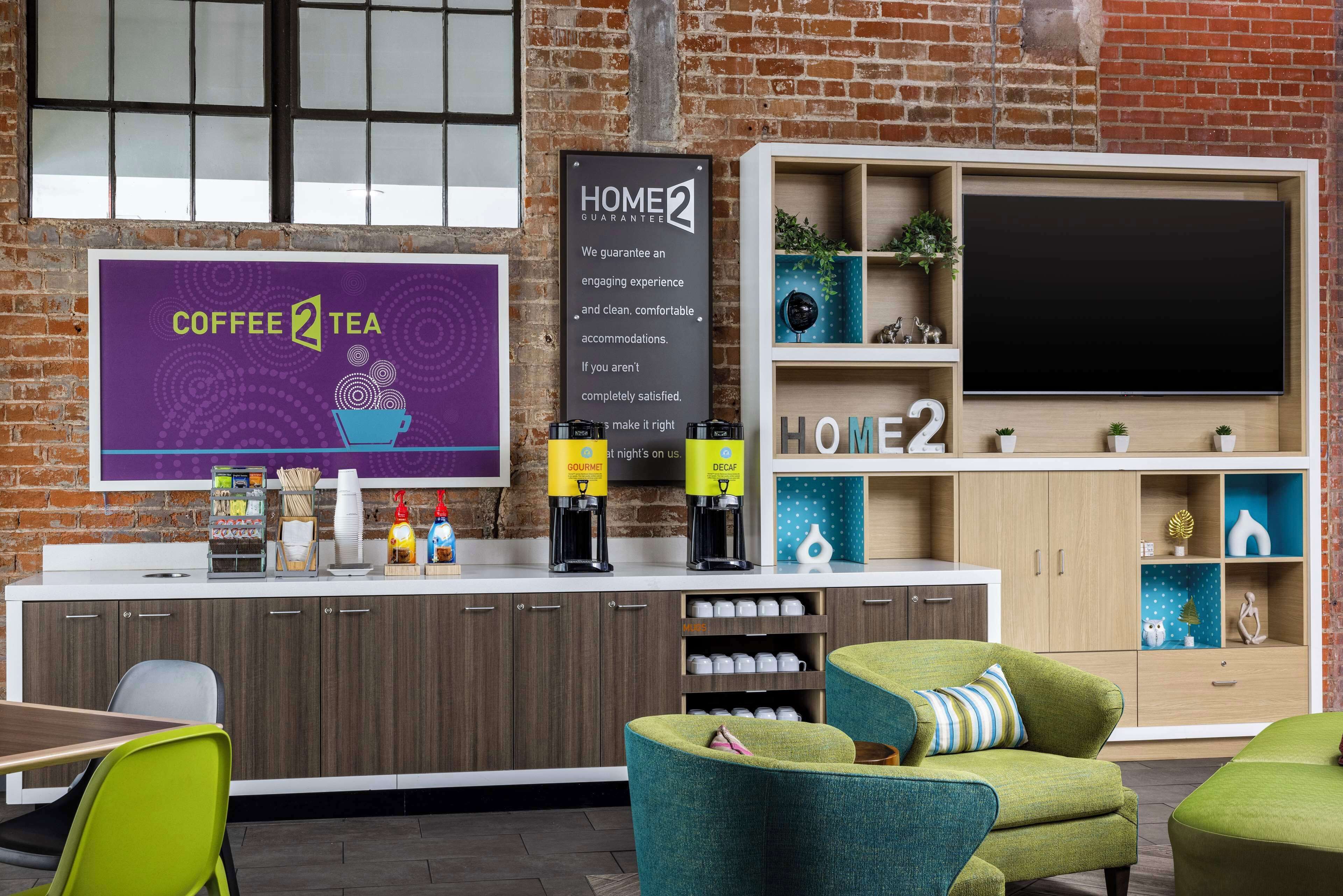 Uma cafeteria moderna com balcão, área de estar e uma grande tela de televisão.