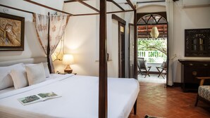 Um quarto espaçoso com cama de dossel, mesa de cabeceira com luminária e vista para a varanda externa.