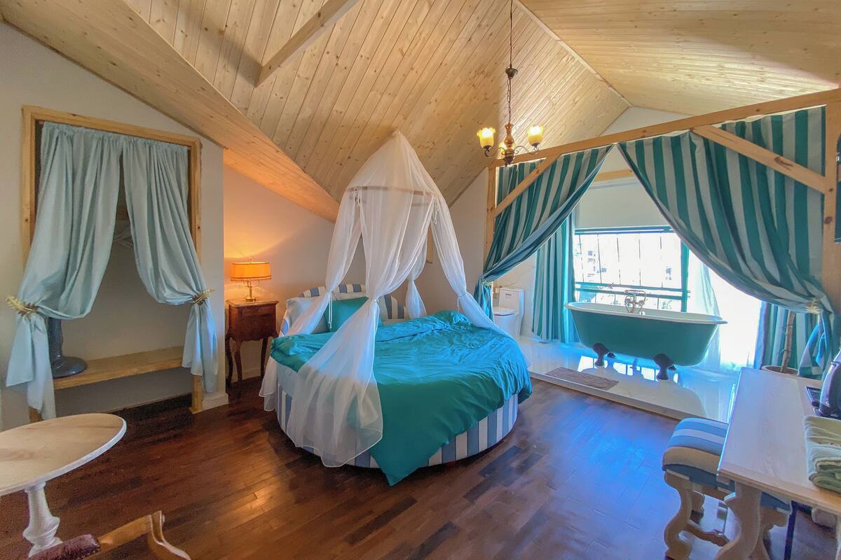 Quarto com cama de dossel, banheira e teto de madeira.
