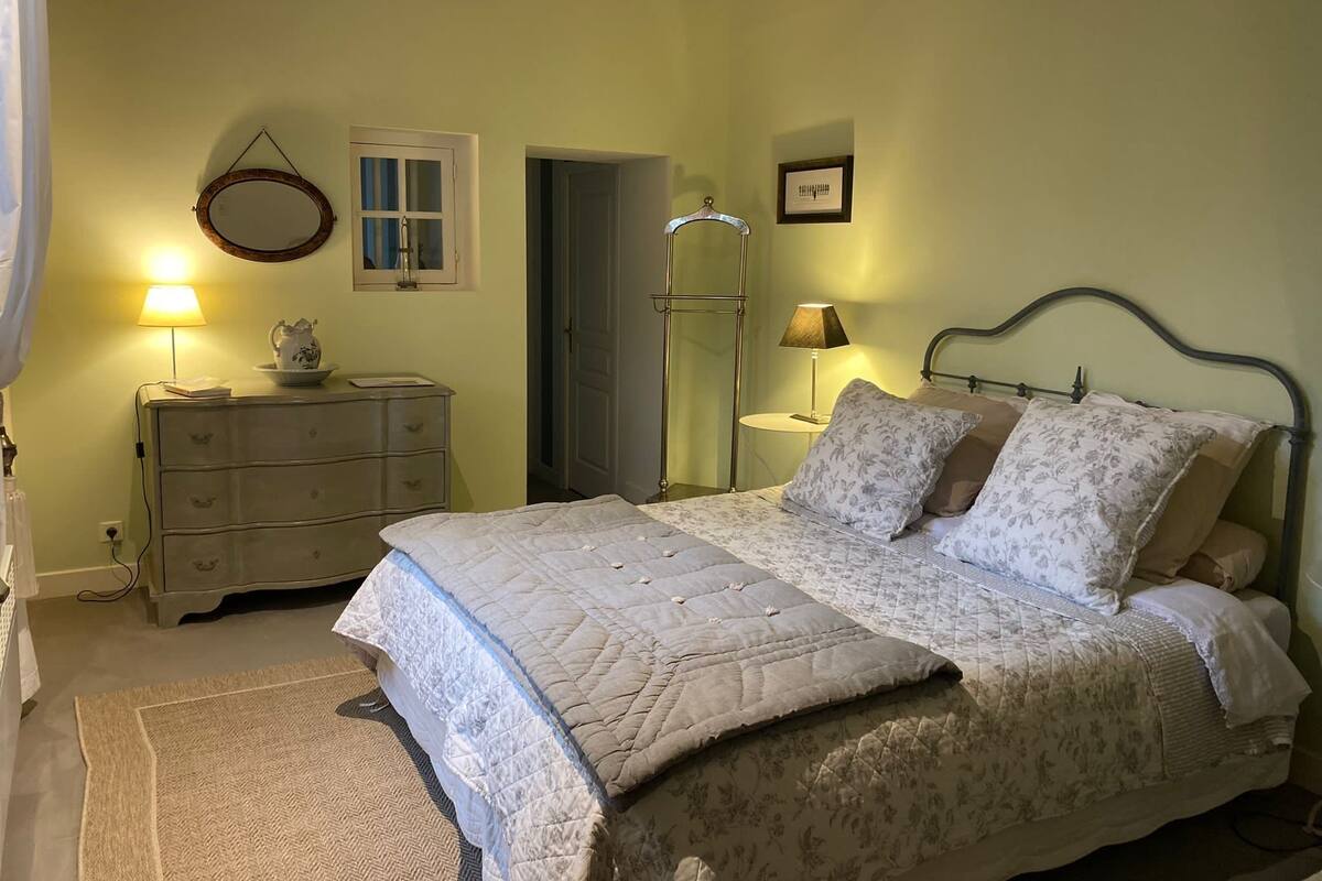 Quarto com cama, penteadeira e duas mesas de cabeceira com luminárias.