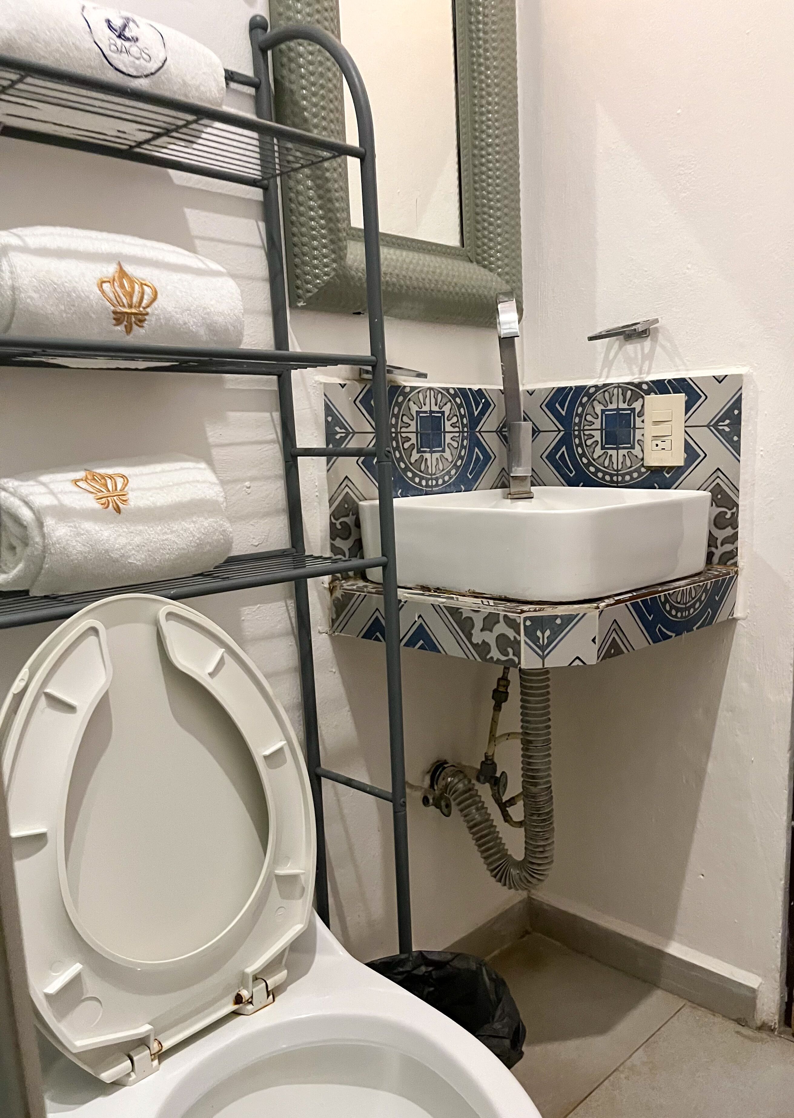 Casa de banho com sanita, lavatório e toalheiros com toalhas.