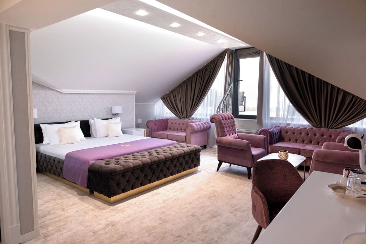 Quarto moderno com uma cama grande, uma chaise longue, um sofá e uma mesa de jantar.