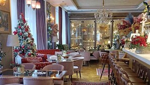 Um amplo hall de hotel com árvore de Natal, assentos de couro, lustres e área de bar.