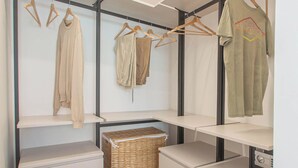 Um closet espaçoso com prateleiras abertas, espaço para pendurar roupas e uma cesta de vime.