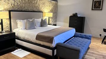 Quarto moderno com cama grande, abajures, penteadeira e um banco.