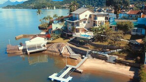 Uma propriedade costeira com um cais, piscina e uma casa grande com várias varandas.