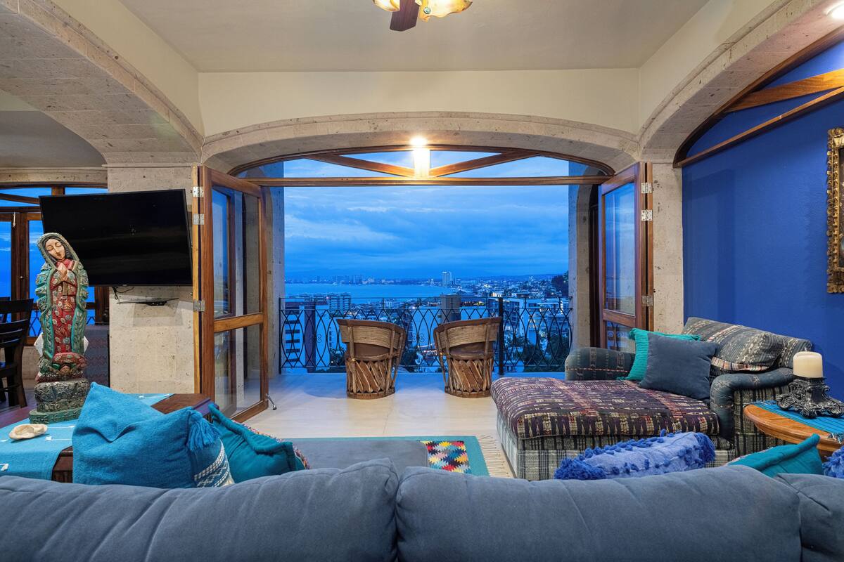 Sala de estar com vista para a cidade, televisão e uma estátua.