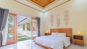 Um quarto espaçoso com uma cama grande, cabeceira de madeira e duas mesas de cabeceira com abajures.