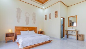 Quarto com cama de madeira, mesas de cabeceira com abajures, penteadeira com espelho e decorações nas paredes.