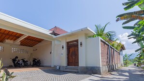 Uma casa de dois andares com entrada em azulejo e varanda coberta.