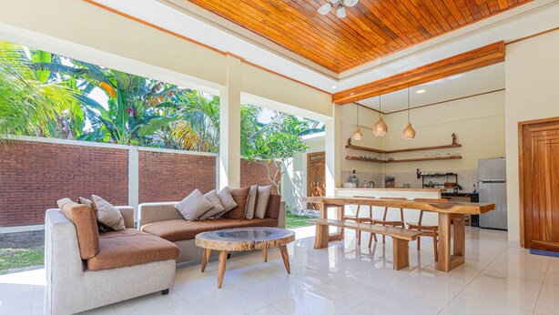 Uma sala de estar moderna com sofá, mesa de centro redonda e mesa de jantar de madeira.