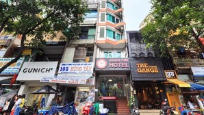 Um hotel com uma placa que diz 'Saigon Pink Hotel' e 'The Central Gangs' na rua.