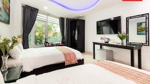 Quarto de hotel com duas camas, televisão, escrivaninha e varanda com cortinas.