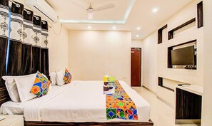 Quarto de hotel moderno com uma cama bem arrumada, televisão de tela plana na parede e ventoinha de teto.