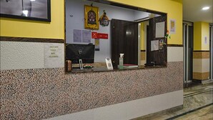 Uma área de recepção com balcão revestido de azulejos, um suporte para casacos e uma porta.