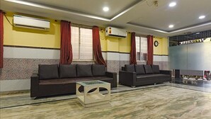 Um hall de hotel com dois sofás, uma mesa de centro e aparelhos de ar condicionado nas paredes.