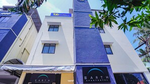 Um edifício de vários andares com placas indicando 'fab Hotels' e 'Earth Apartment Hotel', sinalizando um hotel e complexo de apartamentos.