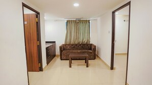 Uma sala de estar com sofá, uma mesa pequena e uma área de cozinha com armários.