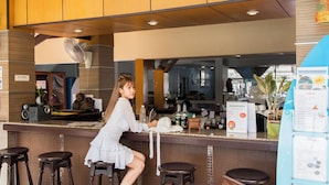 Uma área de bar com uma mulher sentada, um relógio e um quadro de menu.