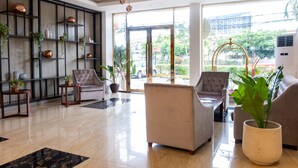Um hall espaçoso com design moderno, apresentando uma grande área de estar, uma parede decorativa com prateleiras e uma janela ampla com vista para o exterior.
