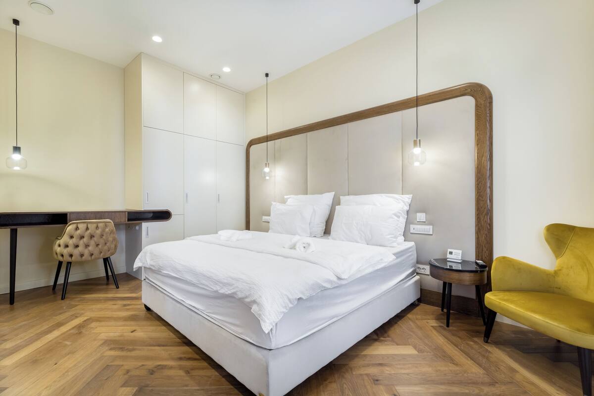 Quarto moderno com uma cama grande, uma escrivaninha, uma cadeira e uma mesinha de cabeceira.