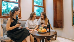 Três pessoas sentadas num sofá e numa mesa com uma fruteira e uma garrafa de vinho.