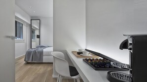 Quarto moderno e minimalista com cama, escrivaninha com um laptop e mesa de centro.